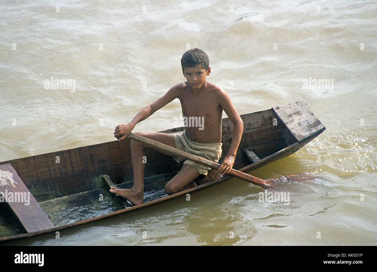 A young Brazilian boy in a dugout canoe on the Amazon River near the ...