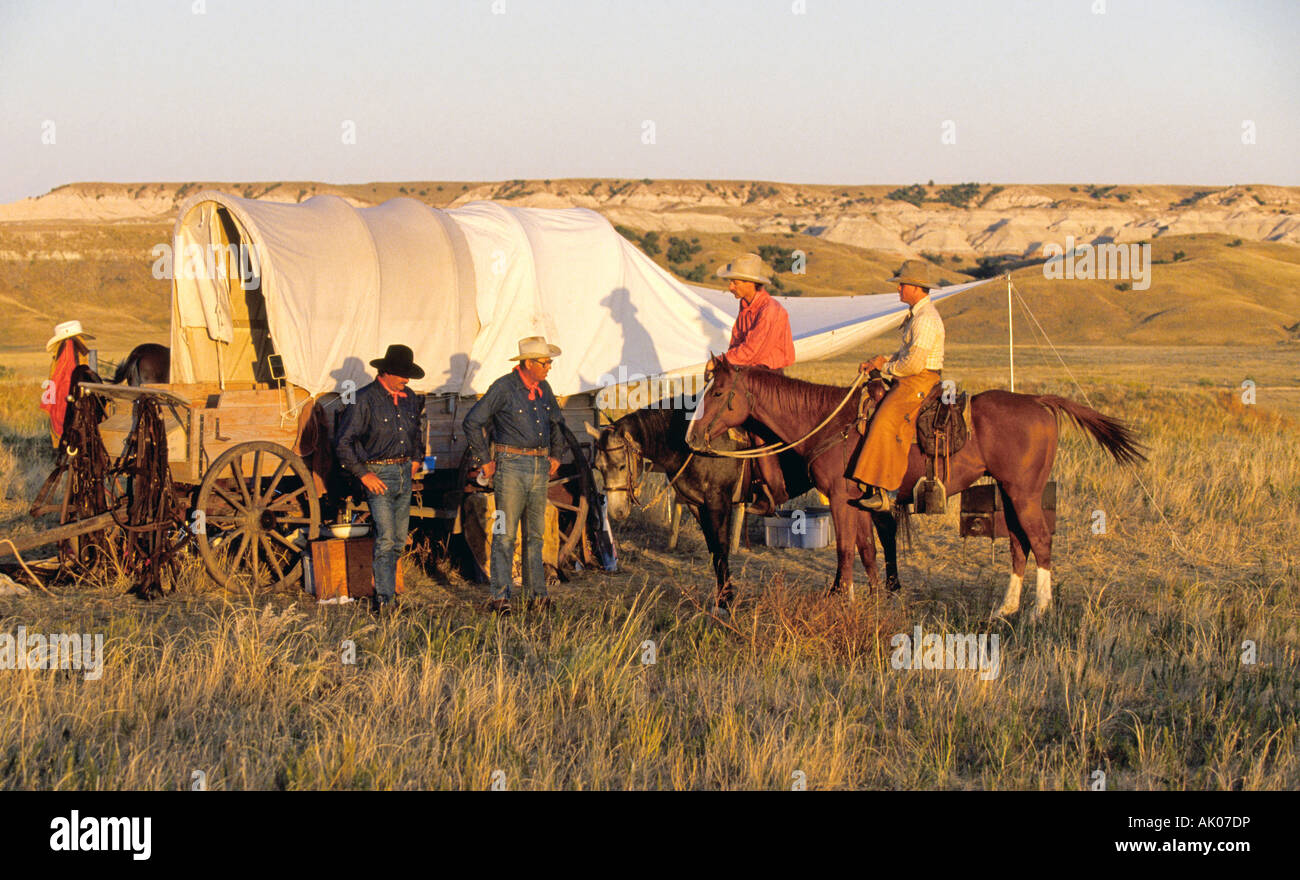 Cowboys on the edge of Badlands National park and a chuck wagon look for cattle on the rolling ...