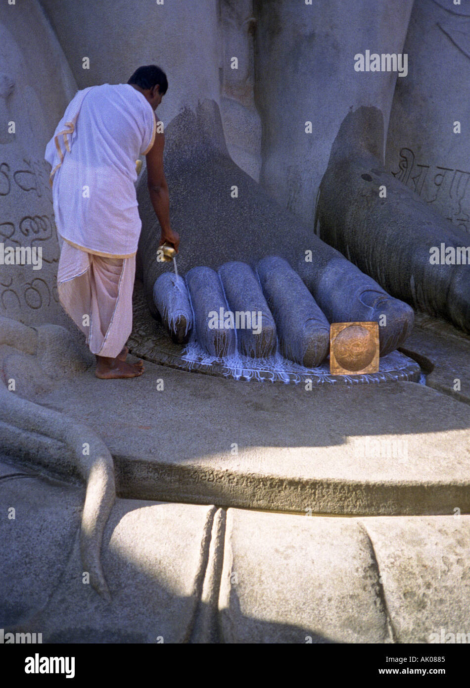 Hindu priest ceremony celebrate pray bless feet foot huge rock Bahubali ...