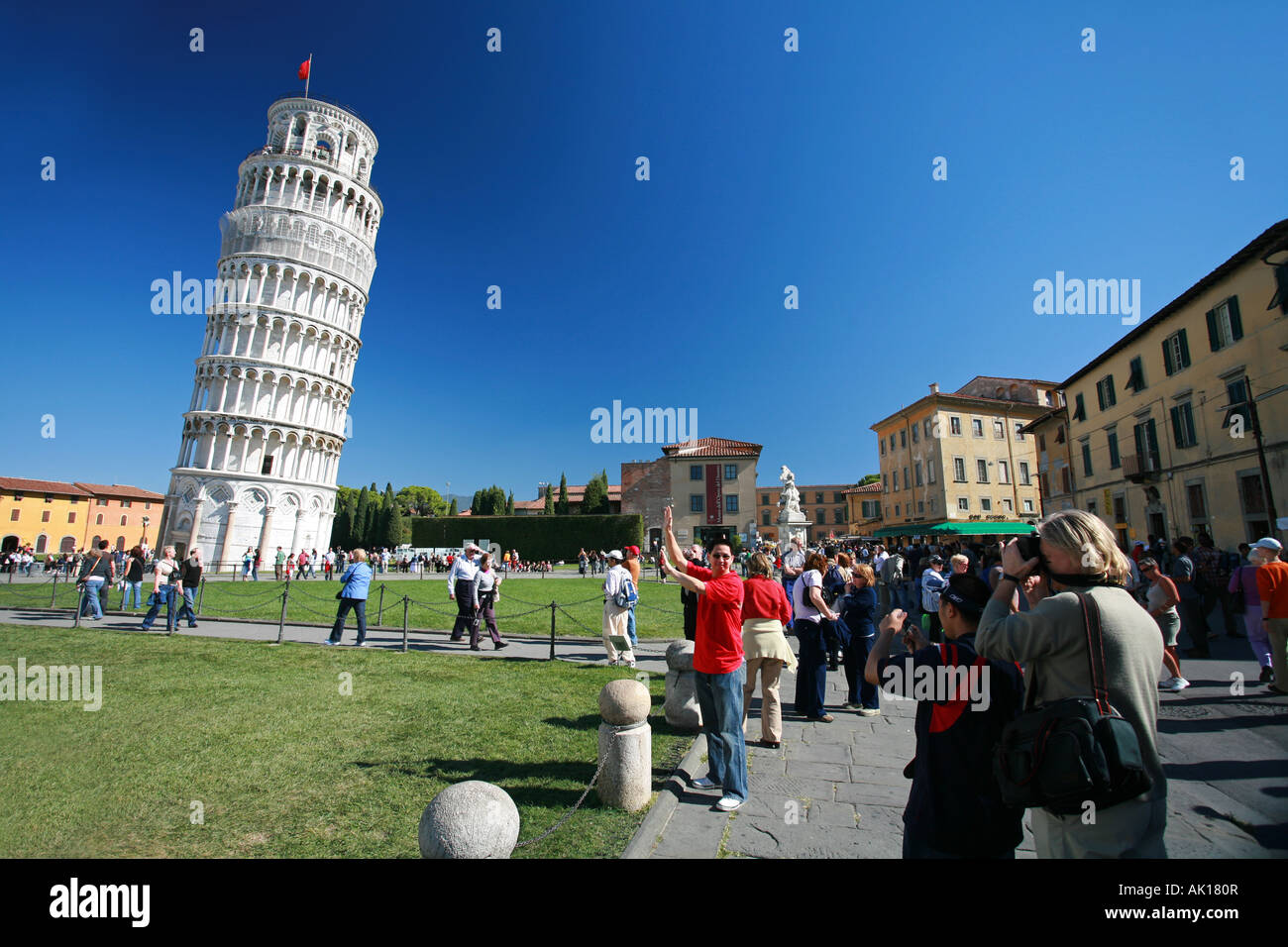 Tourists visitors photograph each other pushing up the leaning tower of ...