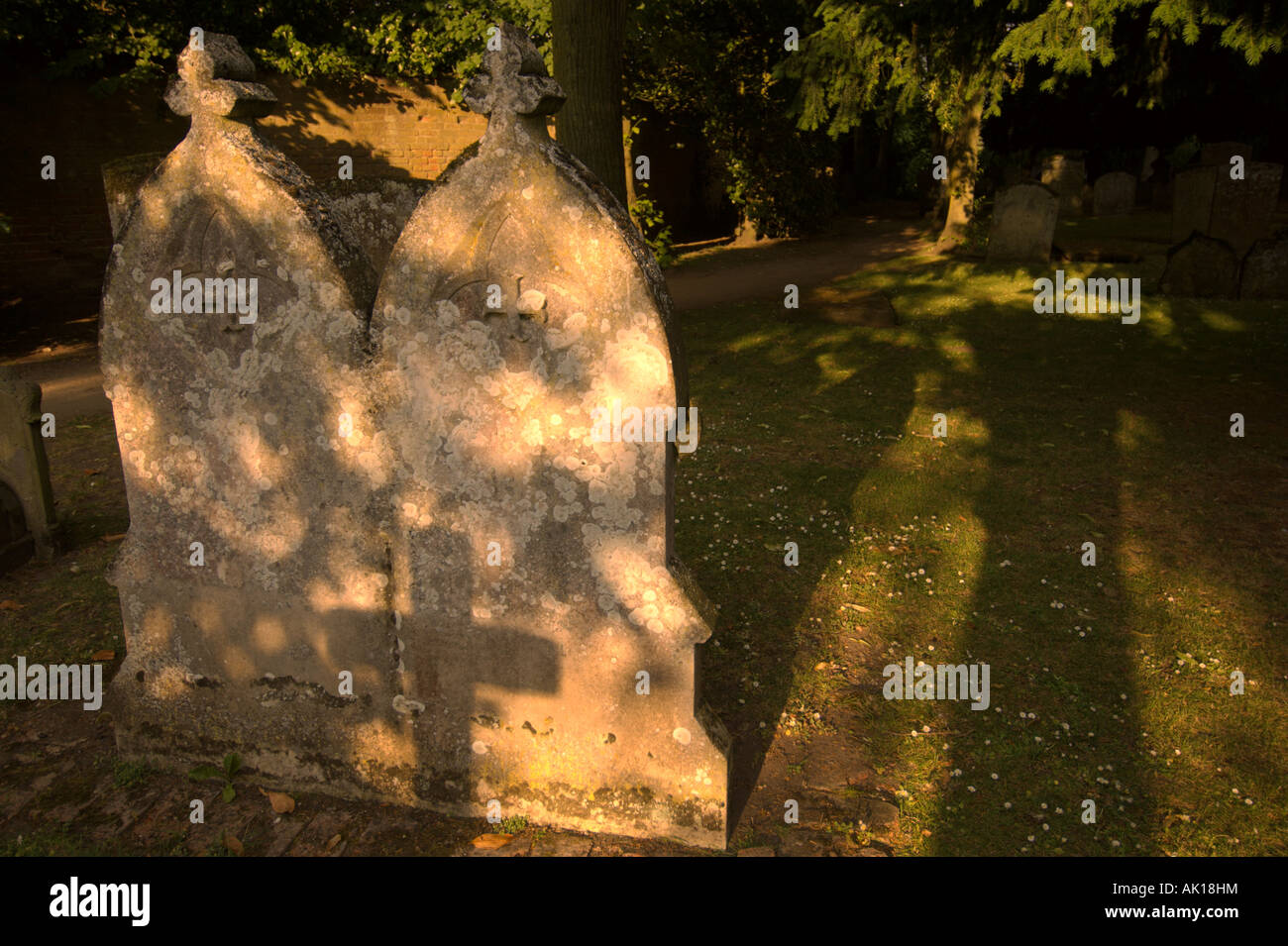 The shadow of a crucifix falls across two grave stones in a graveyard ...