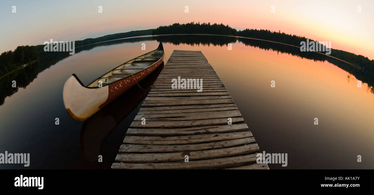 Canoe tried to jetty at sunset Stock Photo - Alamy