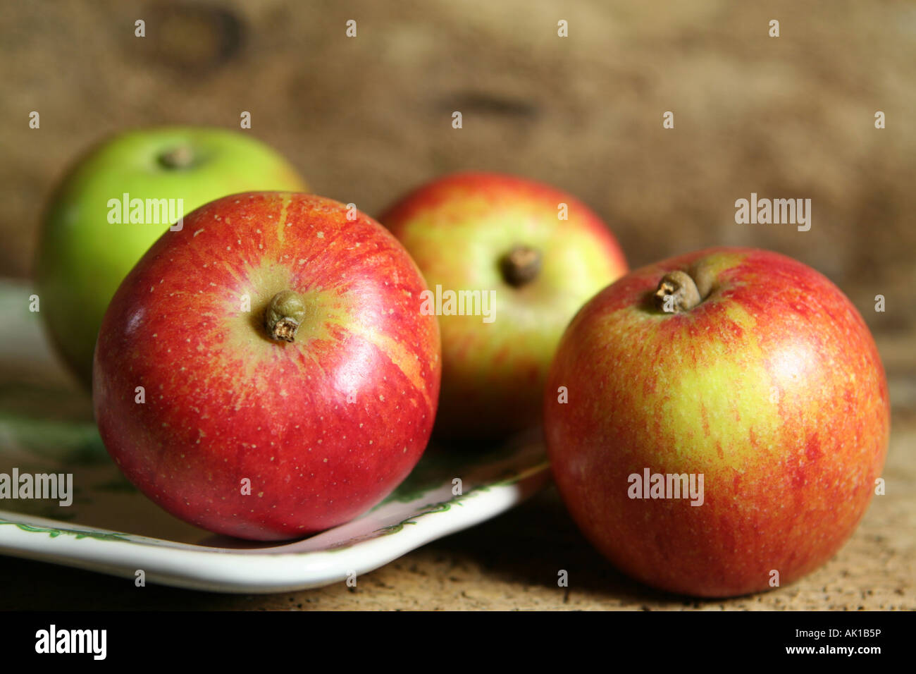 three apples on a decorative plate and one loose Stock Photo - Alamy