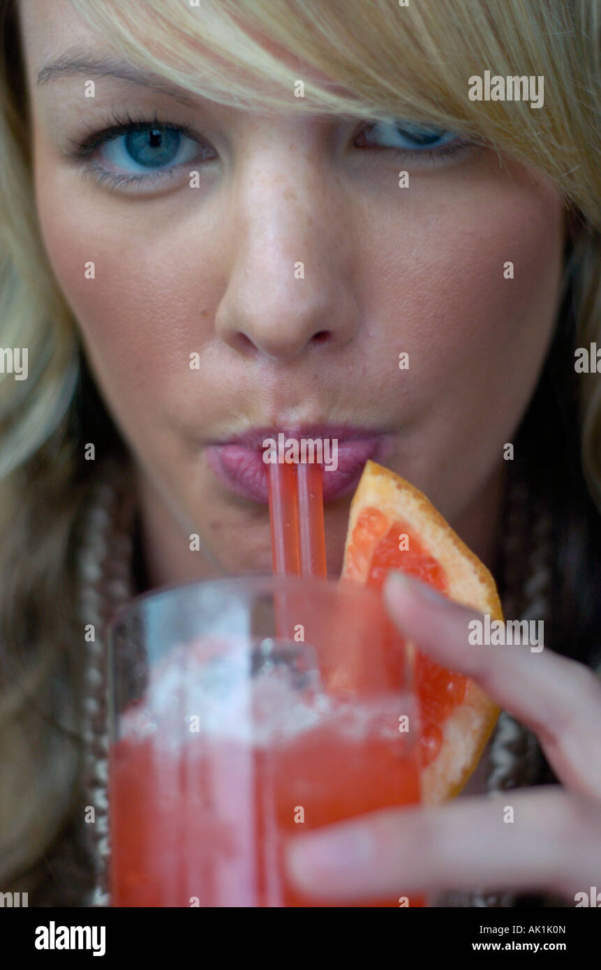 A beautiful woman sips her drink through a straw Stock Photo - Alamy