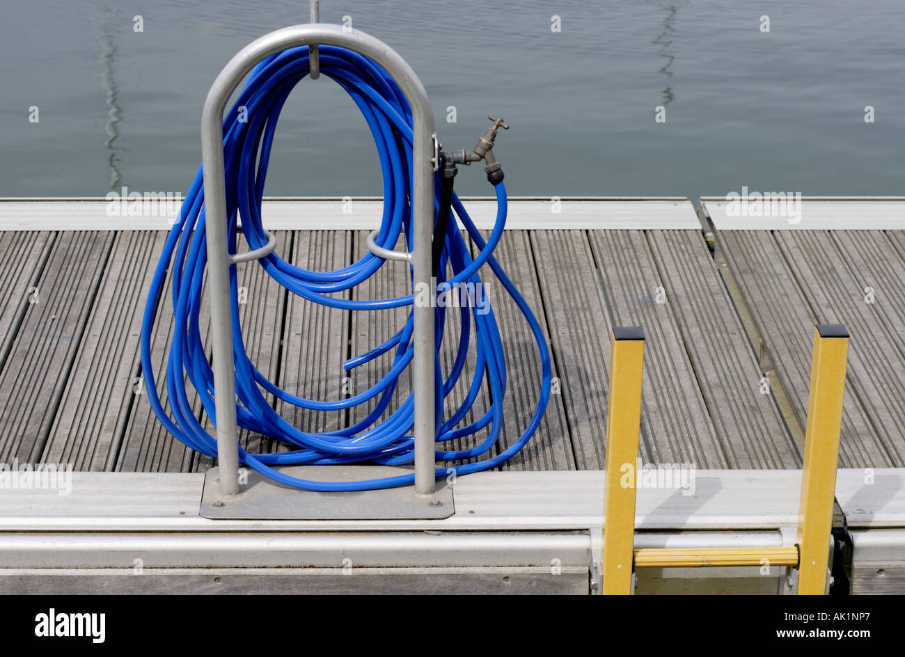 Water supply hose and yellow access ladder on marina quayside Stock ...