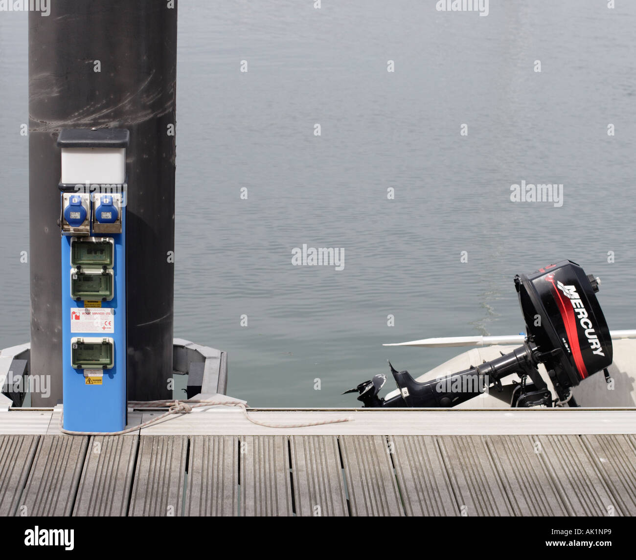 Utility bollard with parked Mercury outboard motor on marina quayside ...