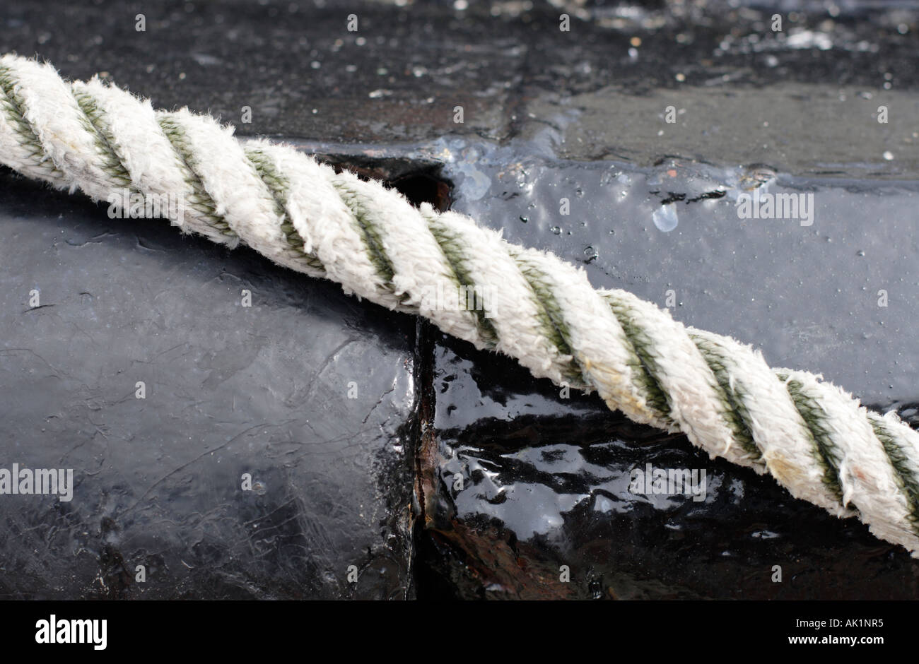 Segment of ships mooring rope on side of black painted deck Stock Photo ...