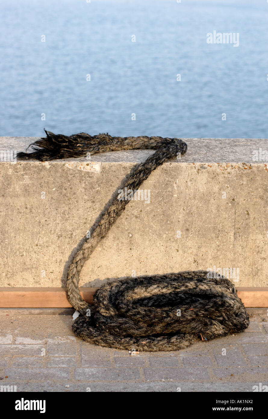 Coil of rope on sea wall resembling a snake Stock Photo - Alamy