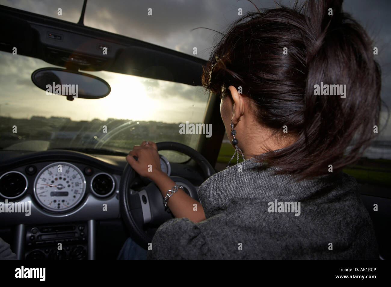 young asian woman driving a mini convertible along the seafront in the ...