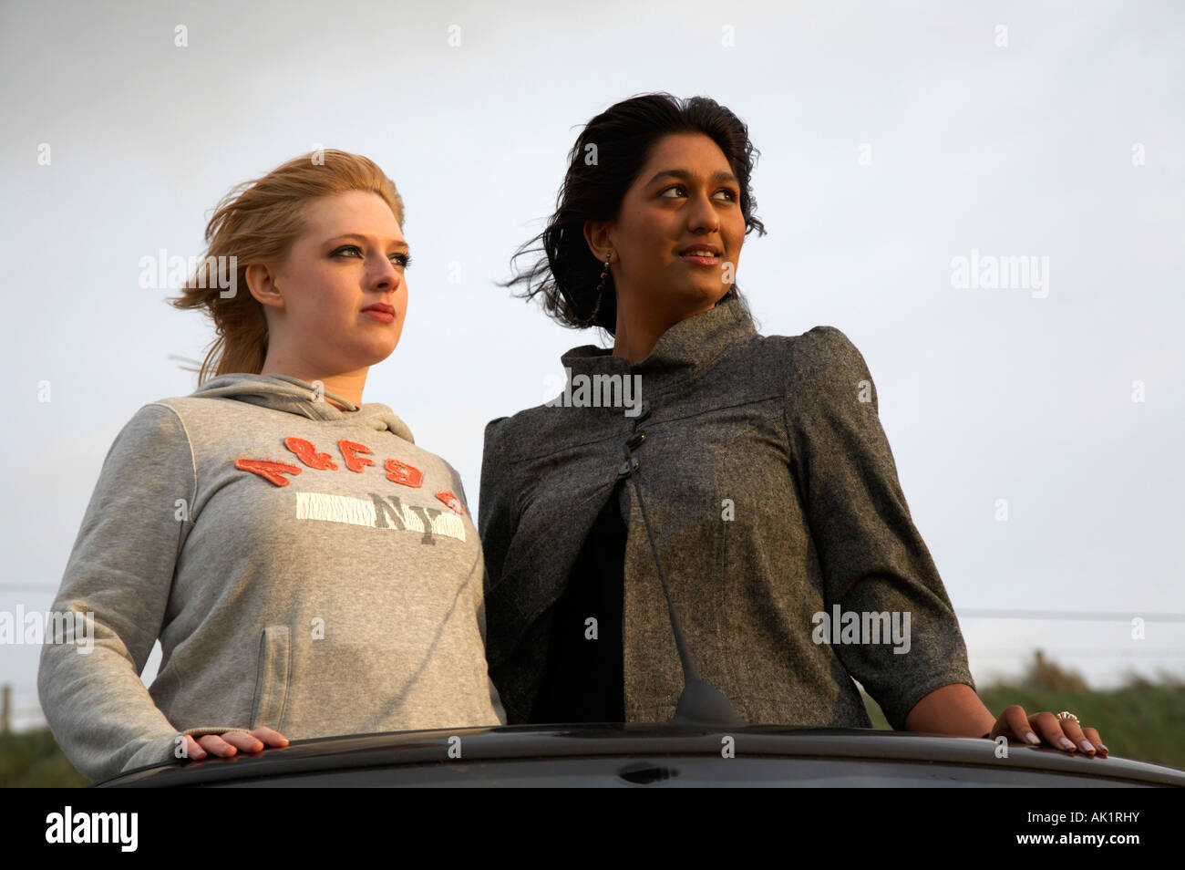 blonde haired irish girl and dark haired asian girl standing looking at ...