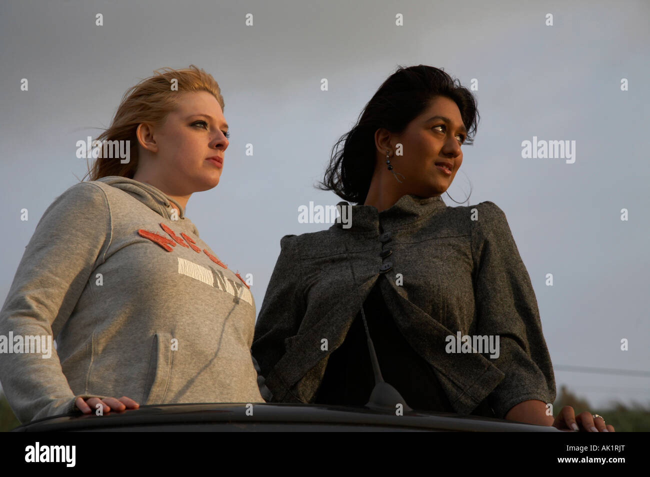 blonde haired irish girl and dark haired asian girl standing looking at ...