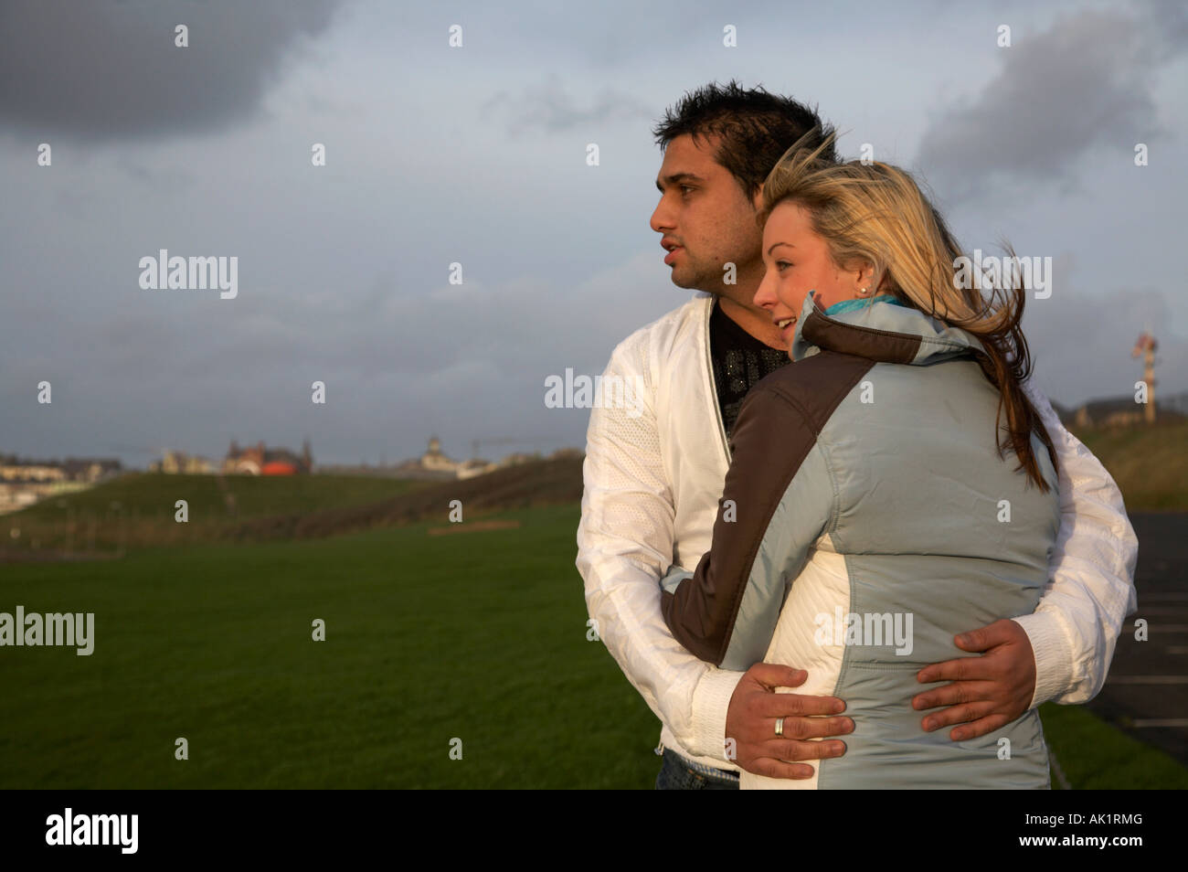 young couple standing embracing looking out across fields Stock Photo ...