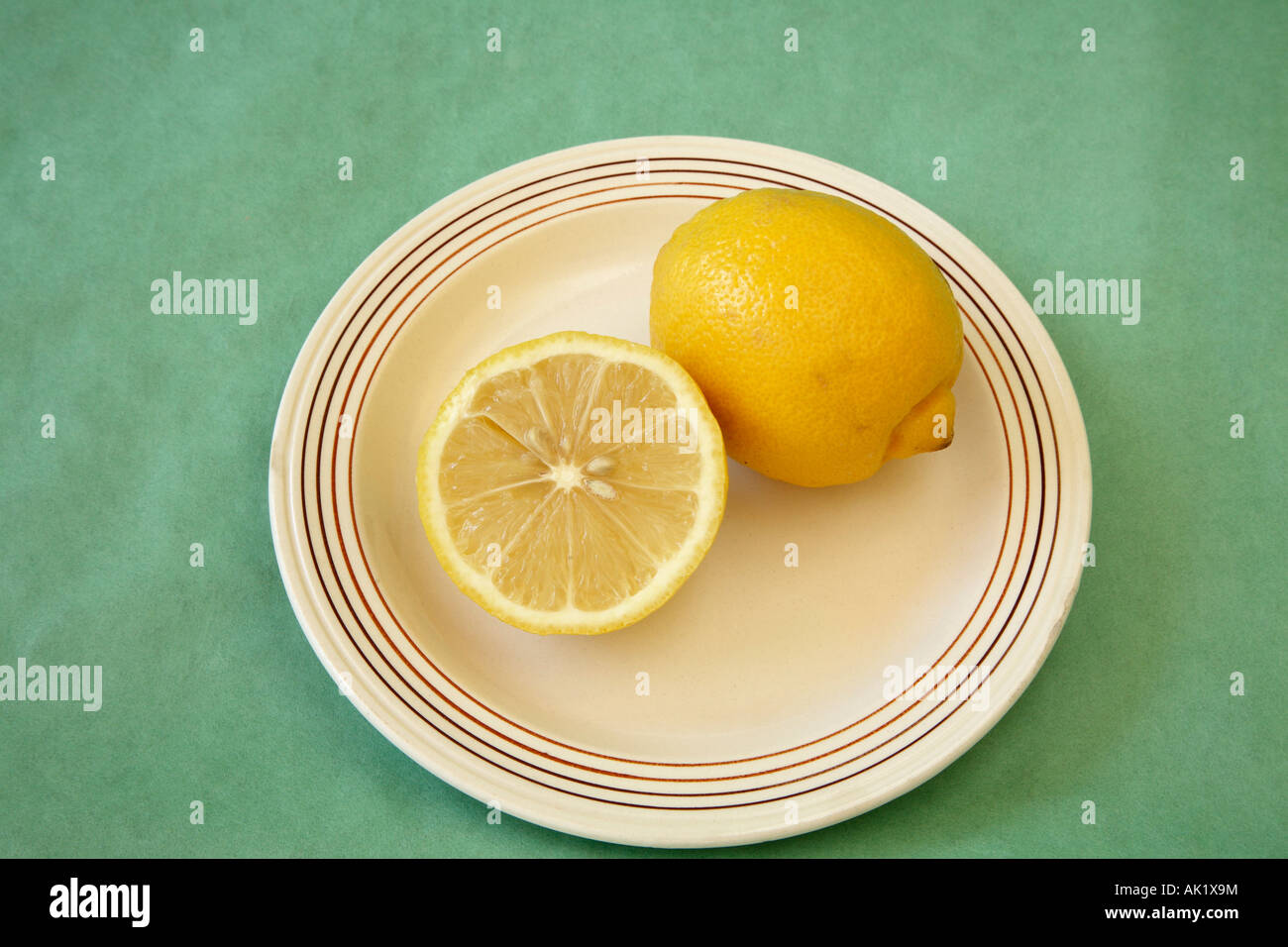 Whole lemon beside a upturned half lemon on small cream colored plate ...