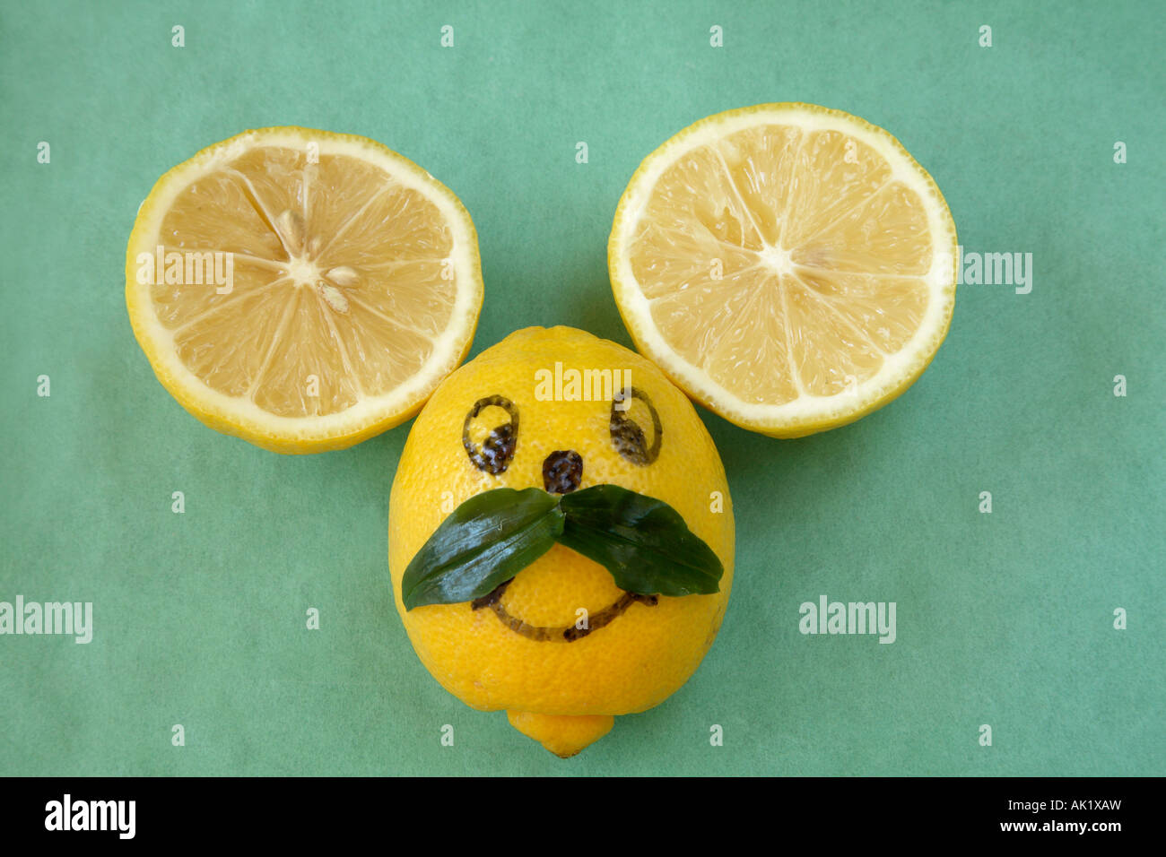 Whole lemon with face drawn on it and two small green leaves used as ...