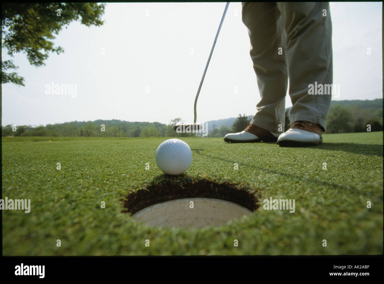Golf ball about to drop into hole Stock Photo - Alamy