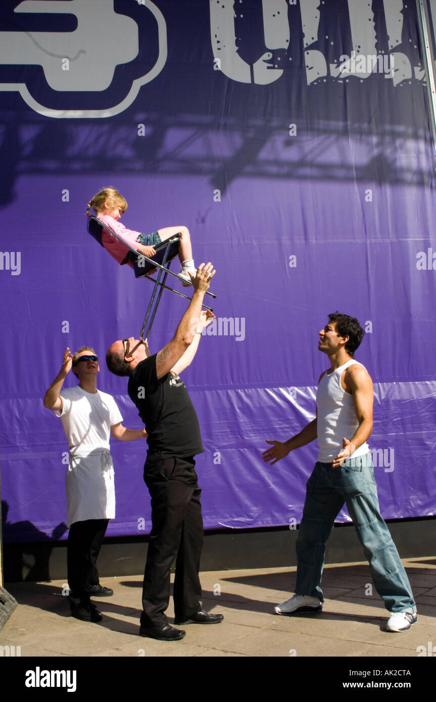 Stuntman balancing on his head a 5 years old girl sitting on a chair ...
