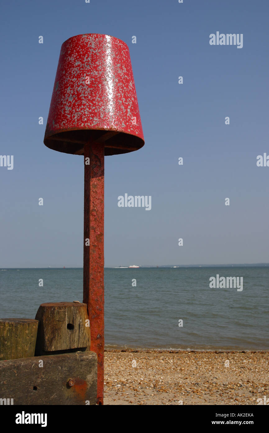 Red metal sea post warning pole on wooden sea defence groyne at Calshot ...