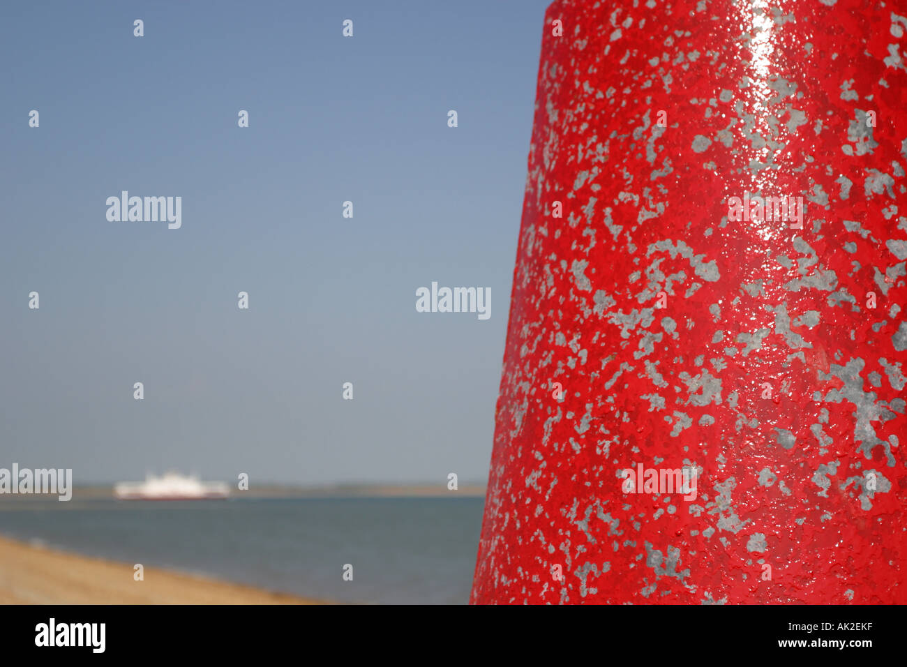Red metal warning post on beach with ship in background Stock Photo - Alamy