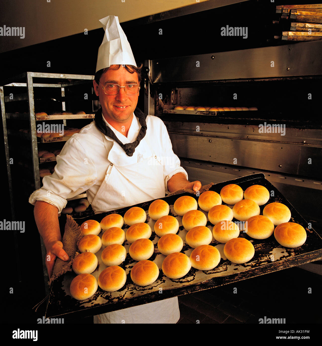 Baker. Chef with batch of freshly baked bread rolls Stock Photo - Alamy