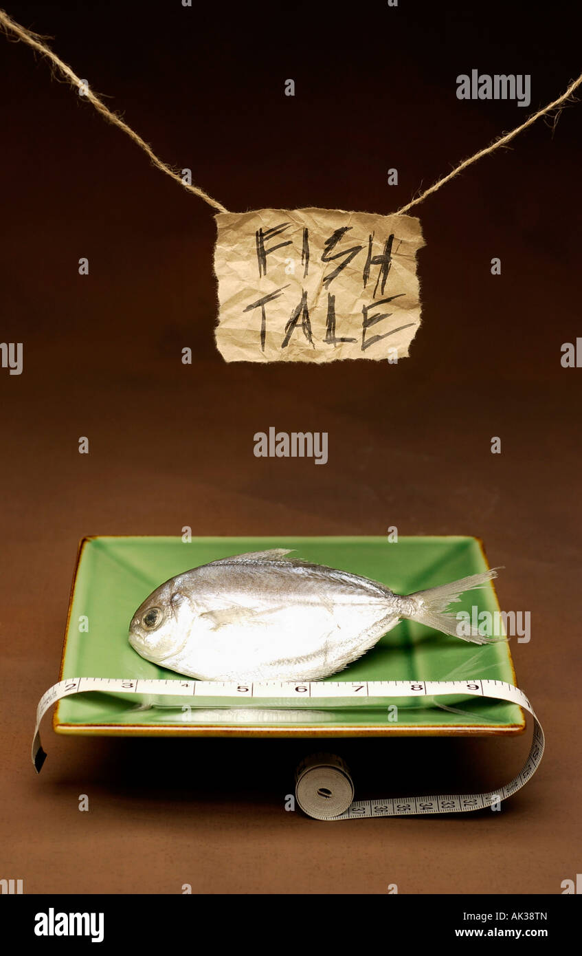 Fish on a plate with a measuring tape and sign saying "fish tale Stock ...