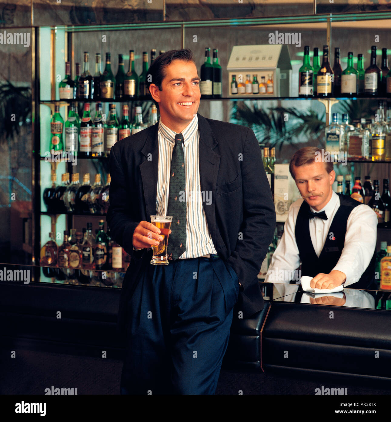 Young man drinking at hotel bar with barman Stock Photo - Alamy