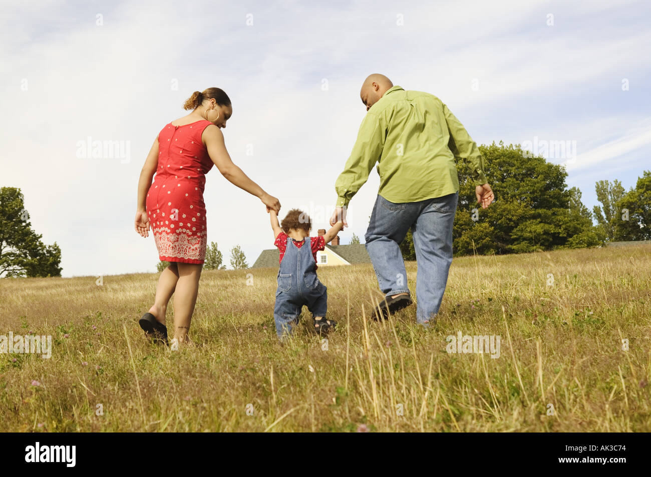 A toddler walking between his mother and father Stock Photo - Alamy