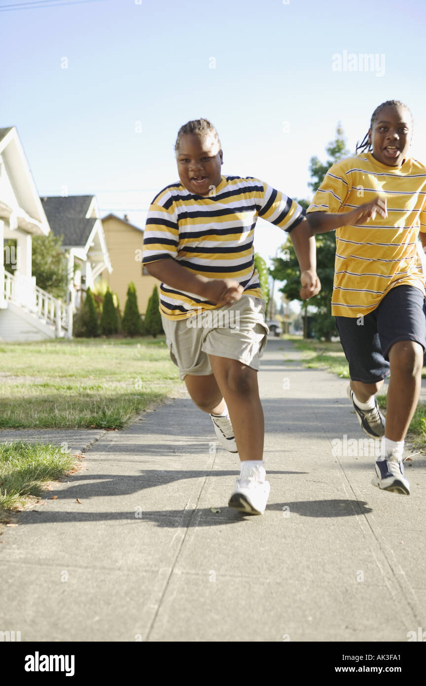 Two boys running down a sidewalk Stock Photo - Alamy