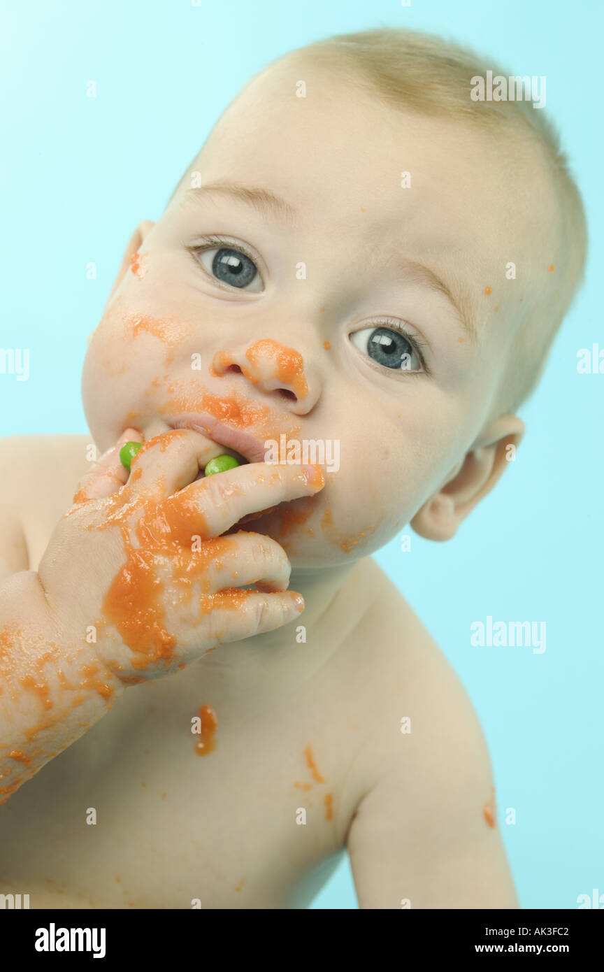 Infant eating baby food with fingers Stock Photo - Alamy