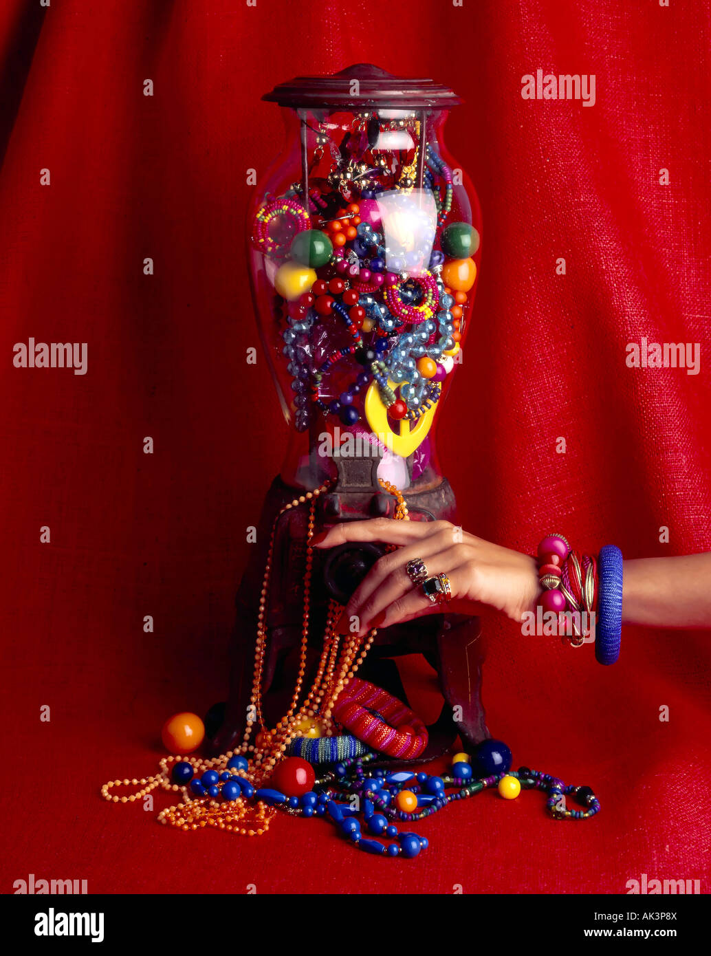 hand with brightly colored jewelry in a old fashion gum ball machine ...