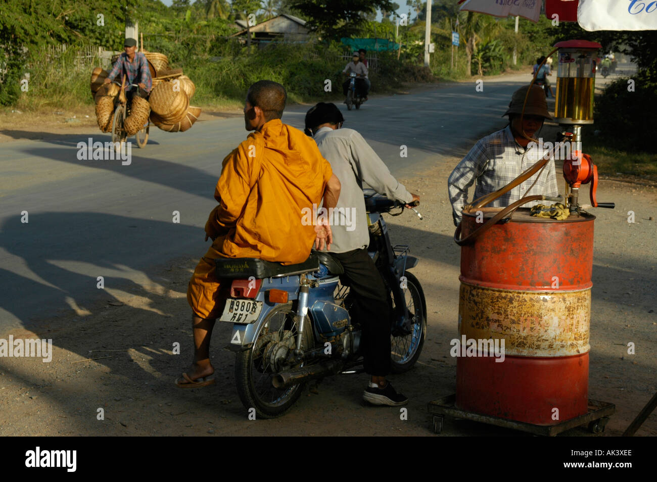Motocycle driver with a monk are driving from a primitive gas station ...