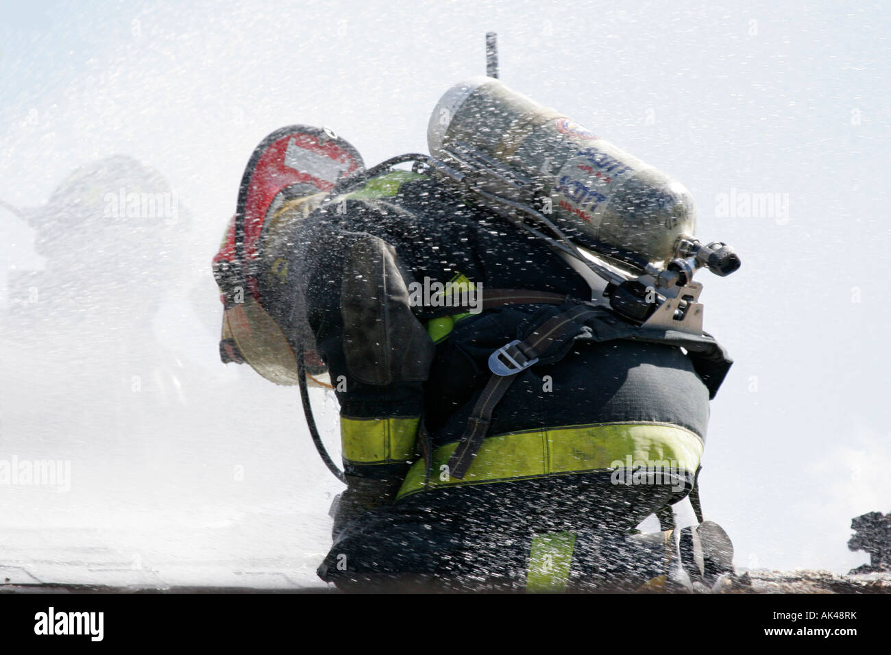 A firefighter on the roof of a church fire in the way of water sprayed ...