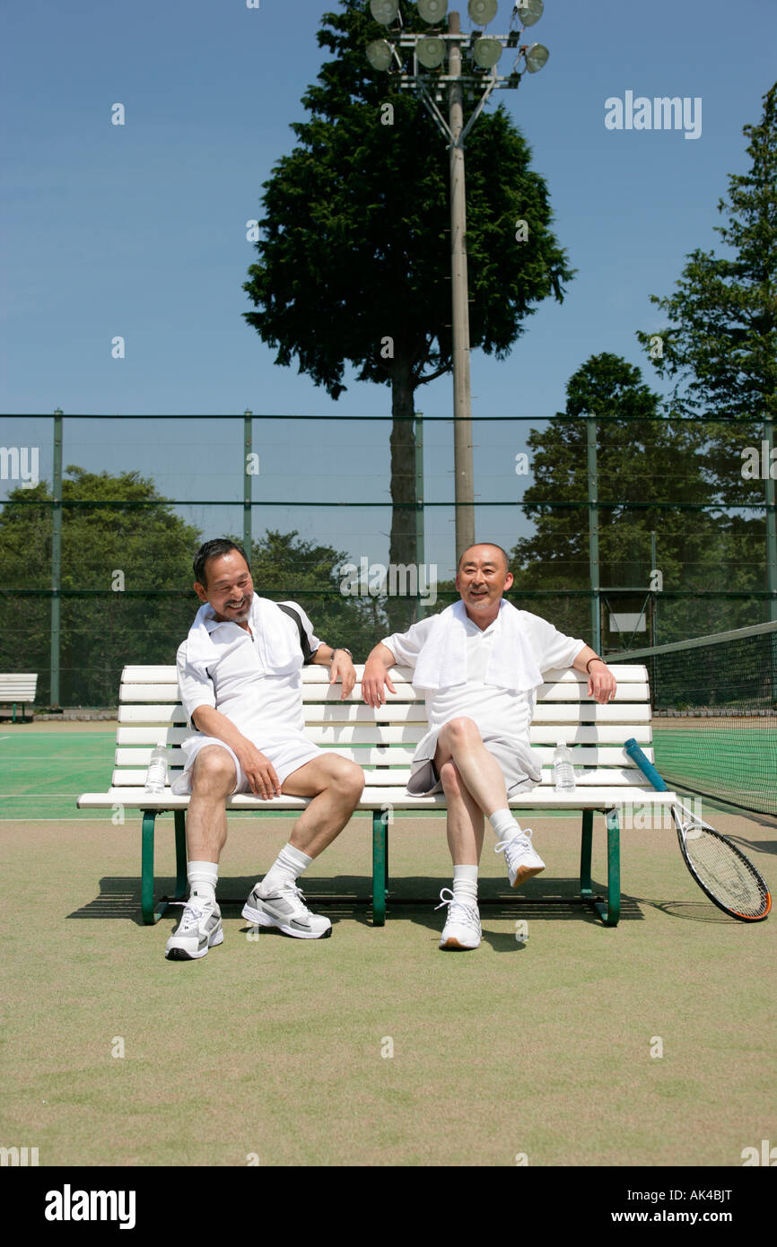 Two mature men sitting on bench in tennis court Stock Photo - Alamy