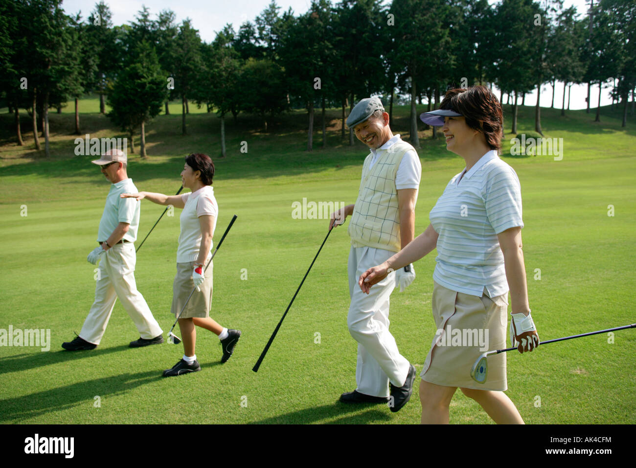 Two couples walking on golf course Stock Photo - Alamy