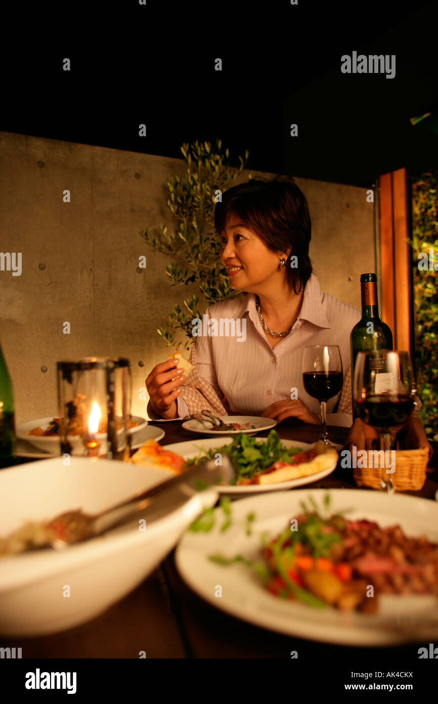 Woman sitting at dinner table, smiling Stock Photo - Alamy