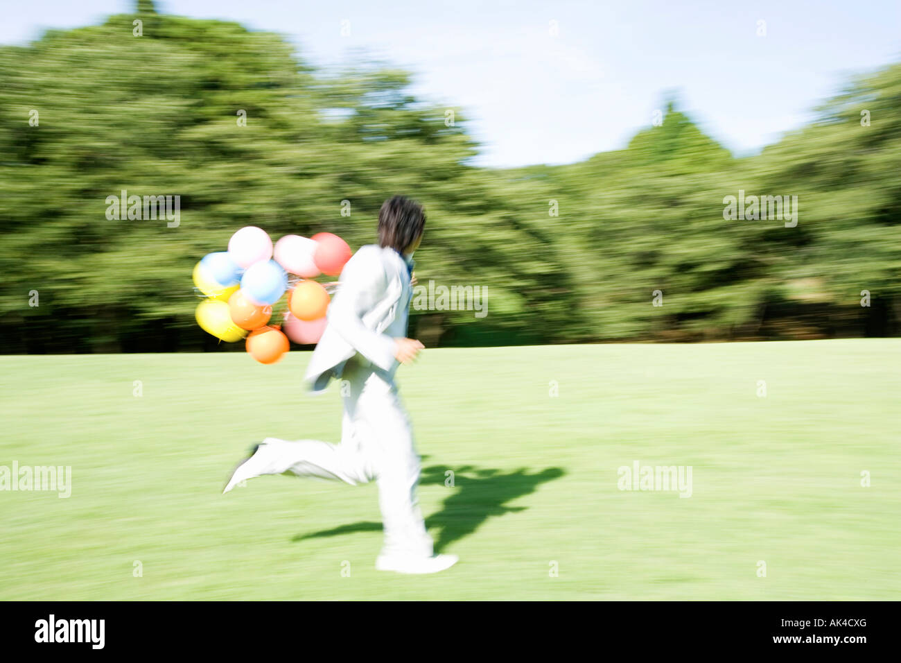 Man with balloons running in the field Stock Photo - Alamy