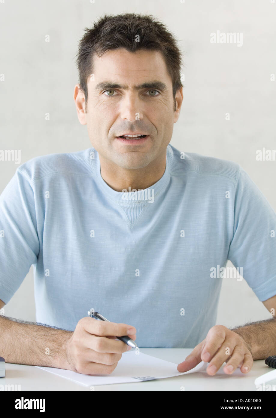 Man writing, looking at camera Stock Photo - Alamy