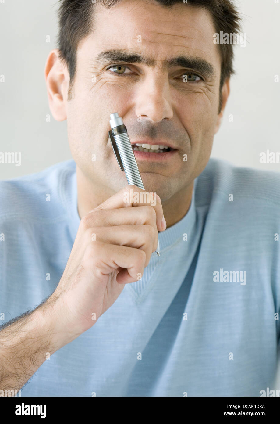 Man holding up pen and looking at camera, close-up Stock Photo - Alamy