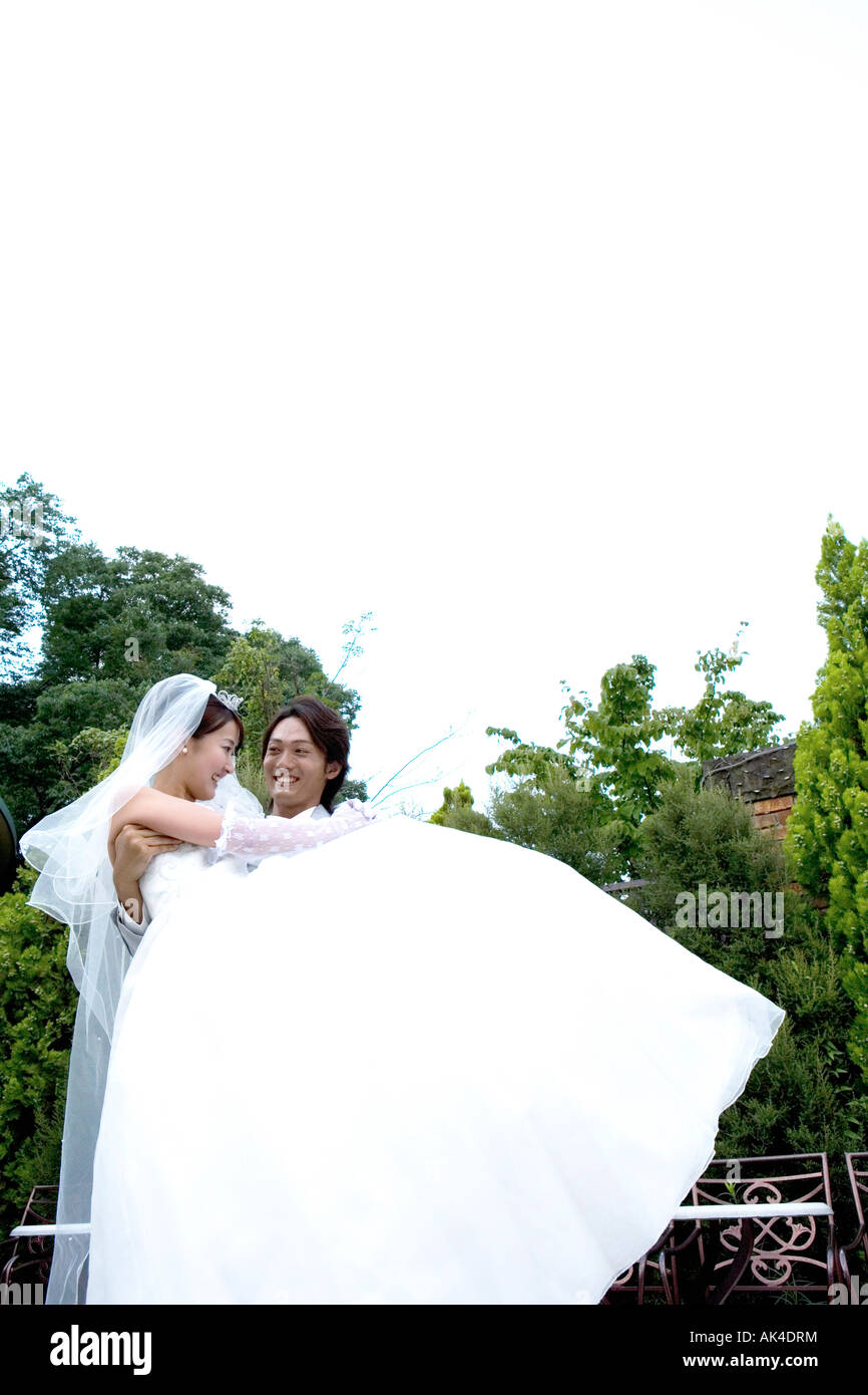 Bridegroom carrying bride in garden Stock Photo - Alamy