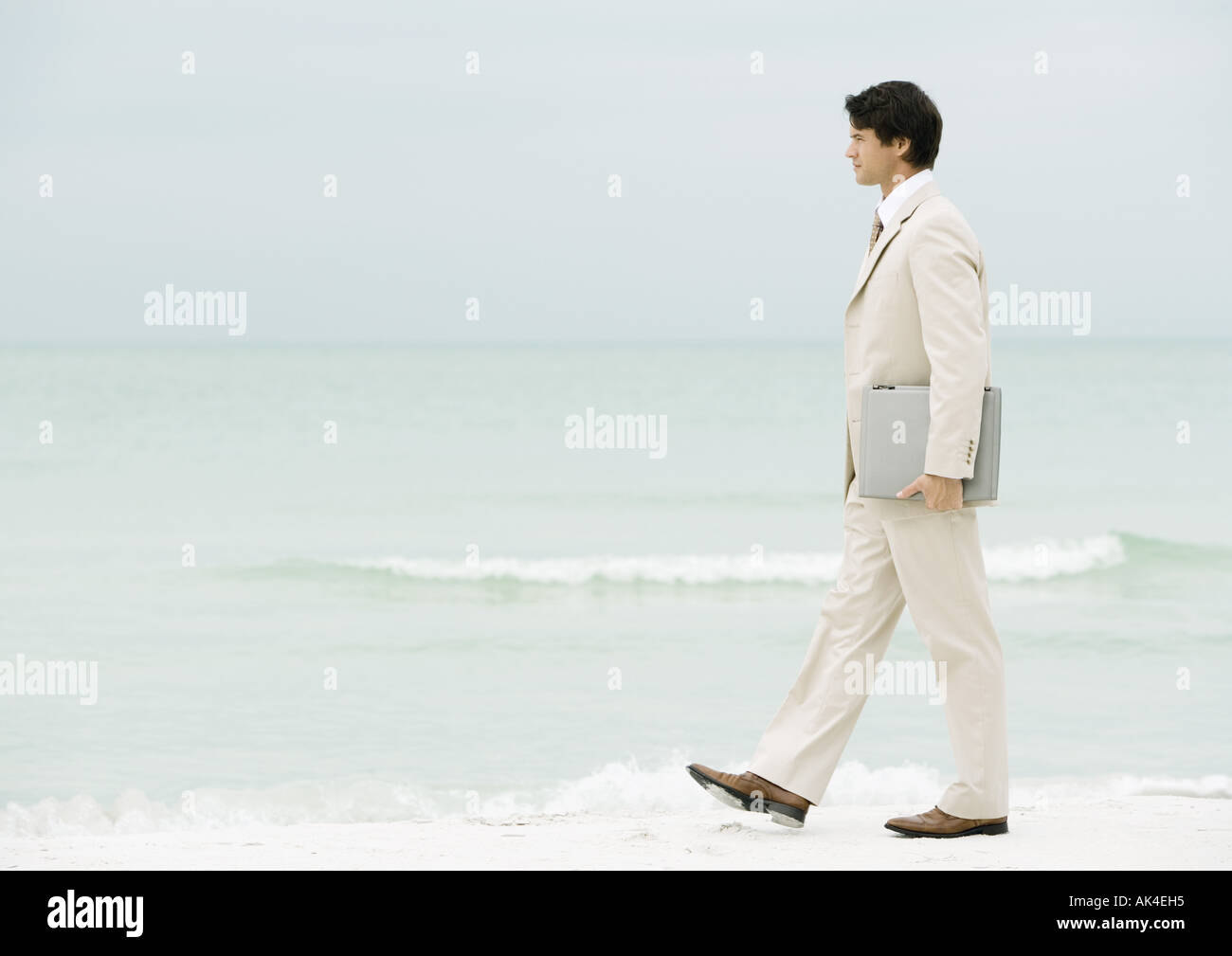 Man carrying laptop under arm, on beach Stock Photo - Alamy