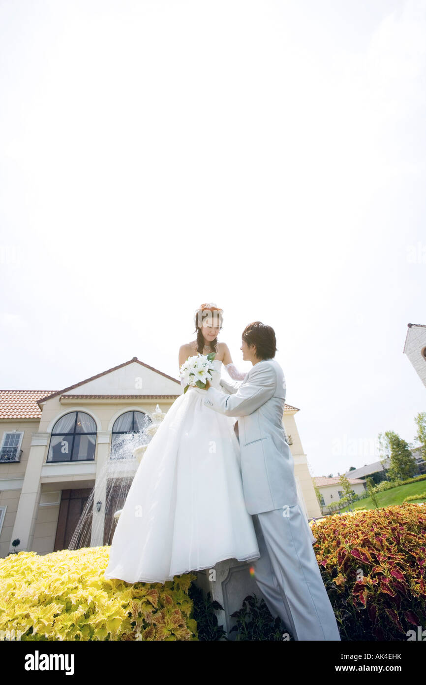Bridegroom lifting bride up in front of house, low angle view Stock ...