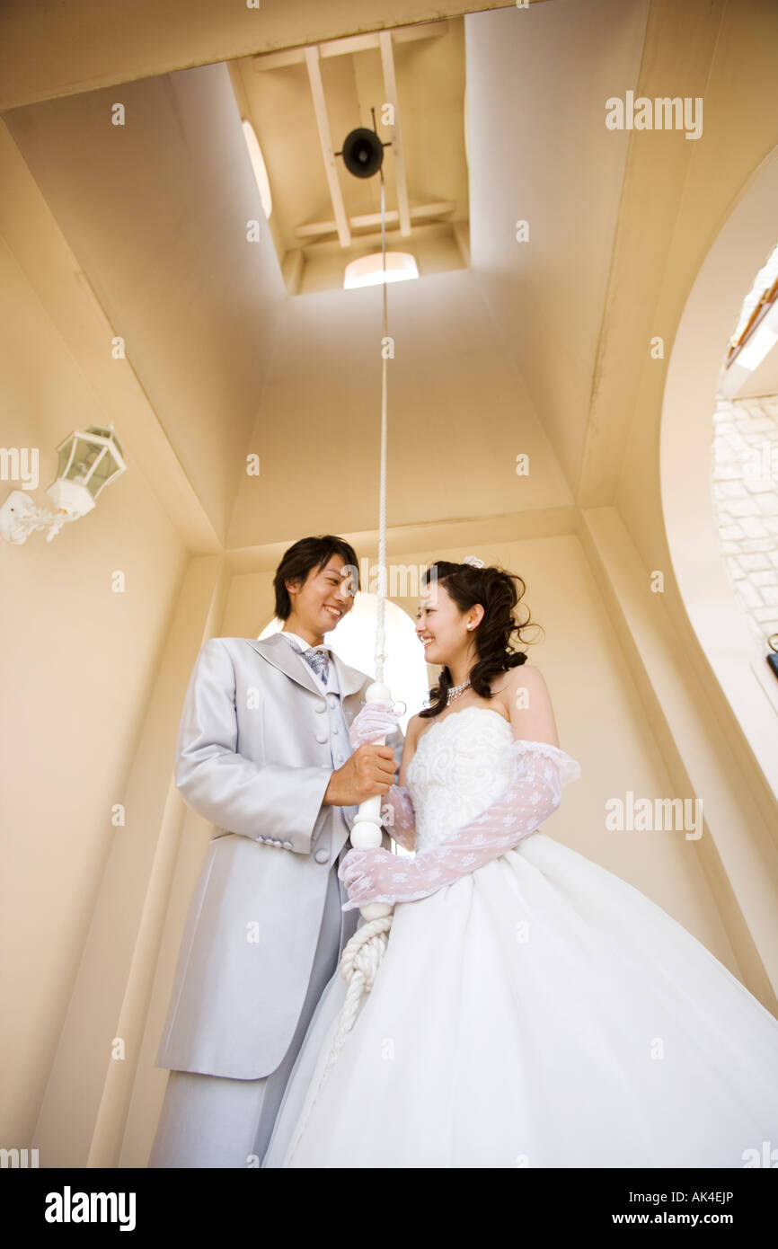 Bride and groom pulling the rope of bell Stock Photo - Alamy