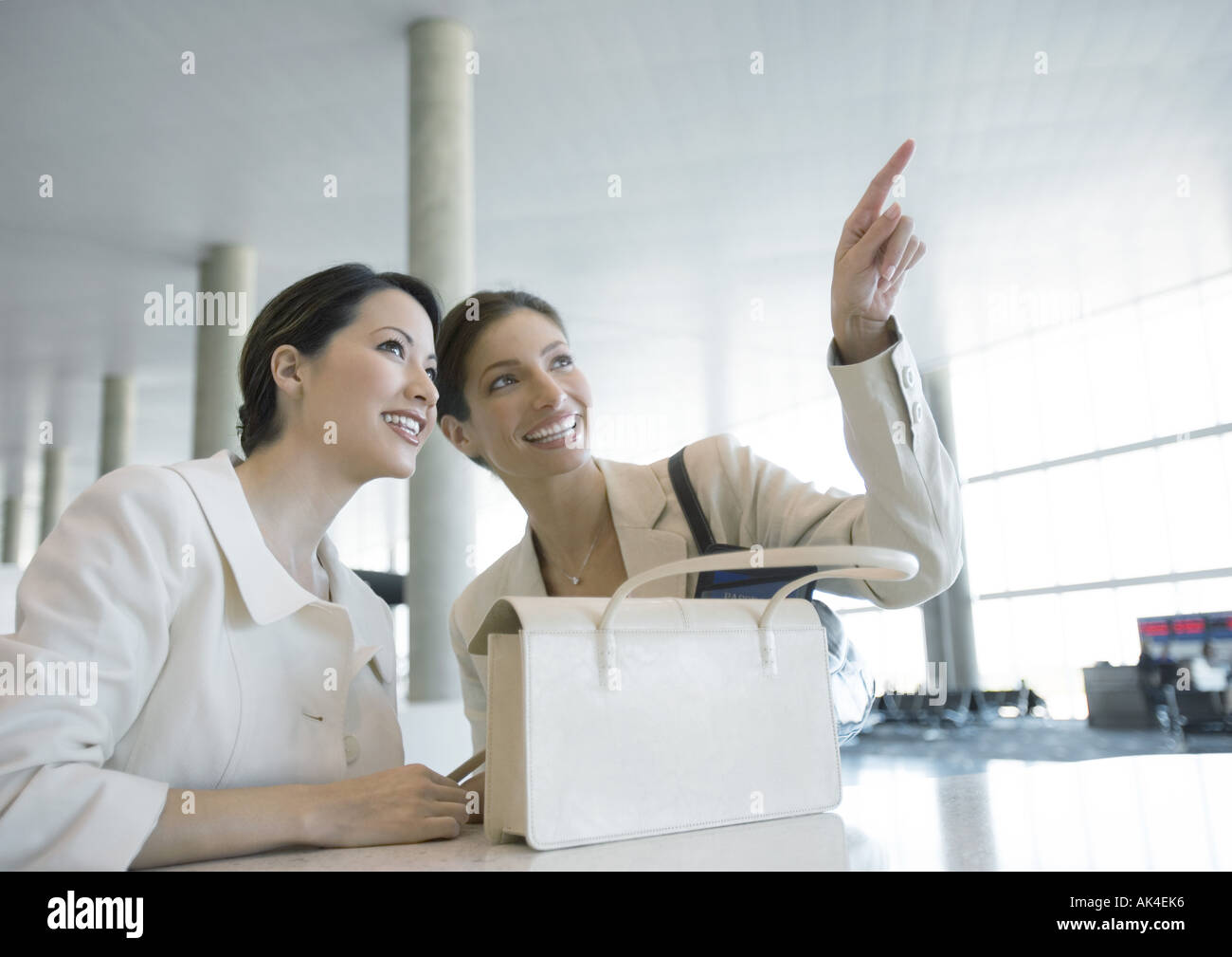 Two women in airport, one pointing Stock Photo - Alamy