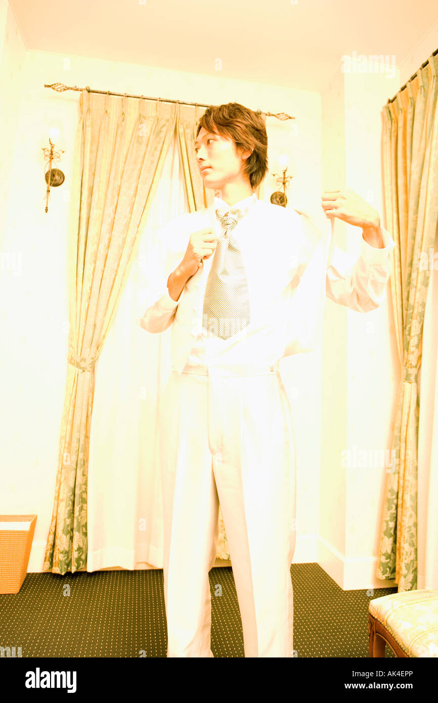 Young man putting on suit Stock Photo - Alamy