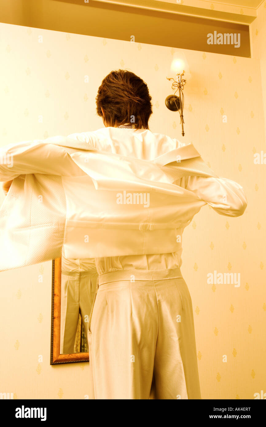Young man putting on jacket in front of mirror, rear view Stock Photo ...