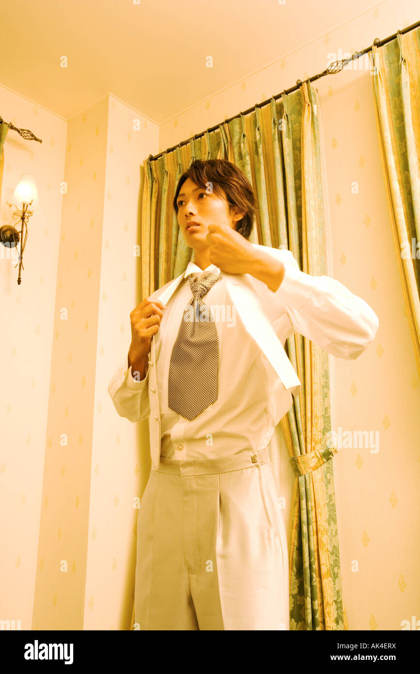 Young man putting on jacket Stock Photo - Alamy