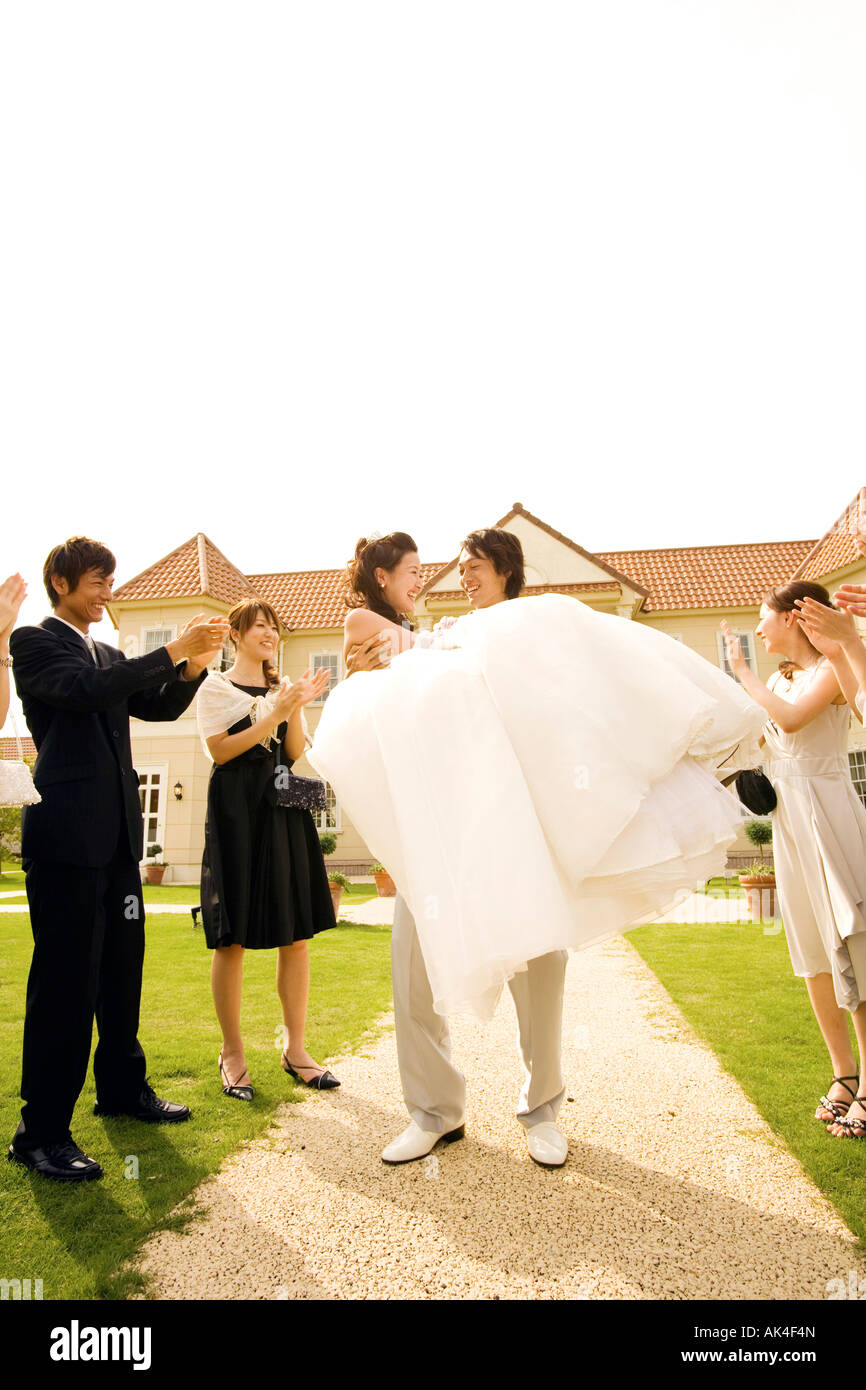 Bridegroom lifting bride, with guests cheering Stock Photo - Alamy