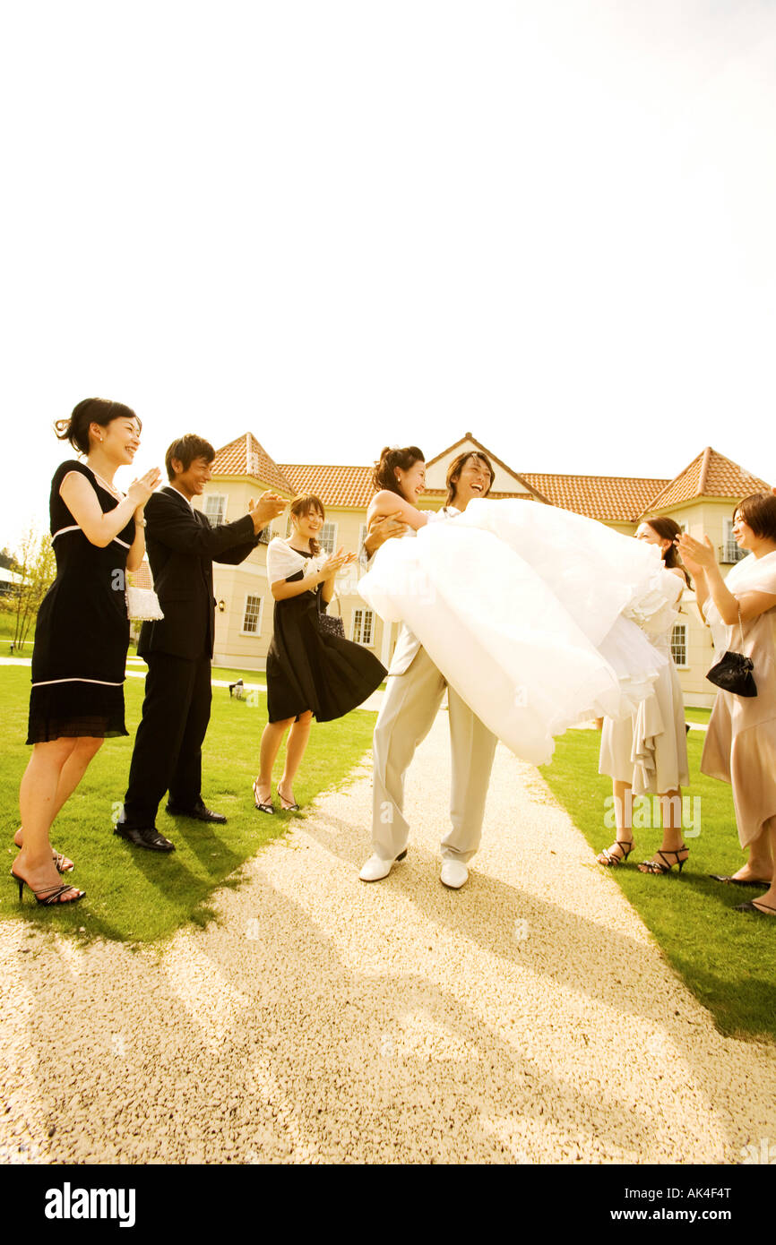 Bridegroom lifting bride, with guests cheering Stock Photo - Alamy