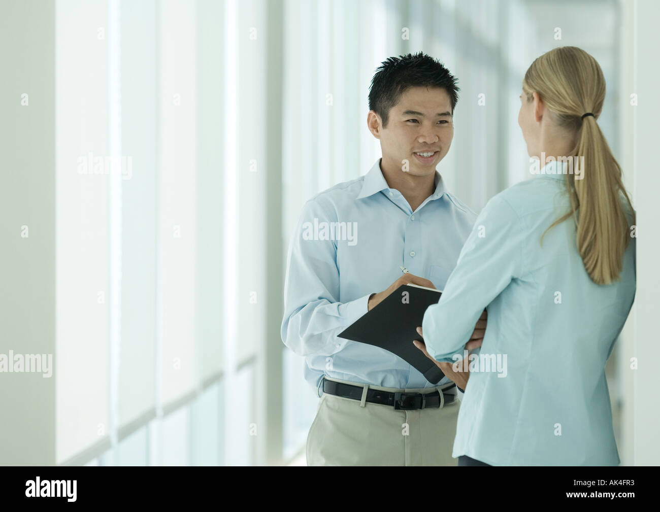 Two office workers talking in corridor Stock Photo - Alamy