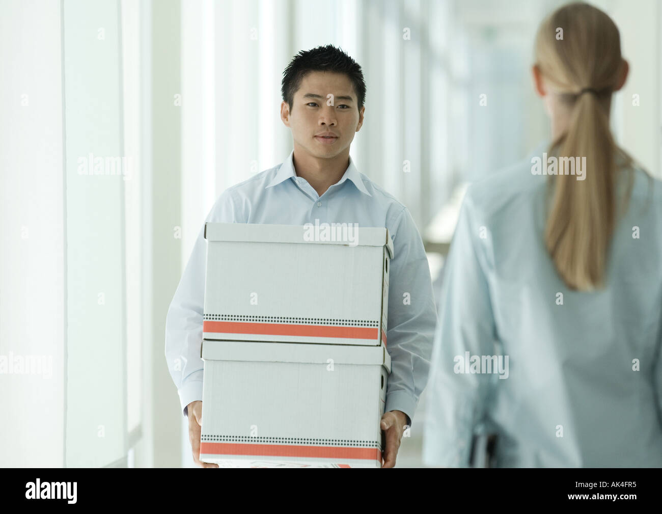 Office worker carrying boxes through corridor Stock Photo - Alamy