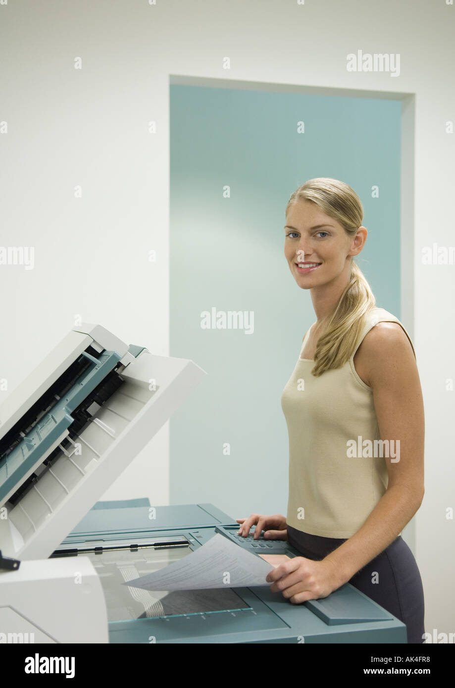 Female office worker standing at copy machine, smiling at camera Stock ...